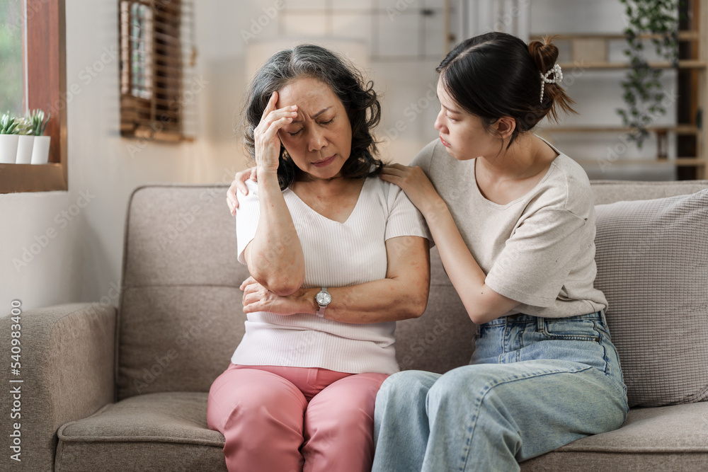 Sad asian mature woman grown up daughter or grandkid sitting on sofa ...
