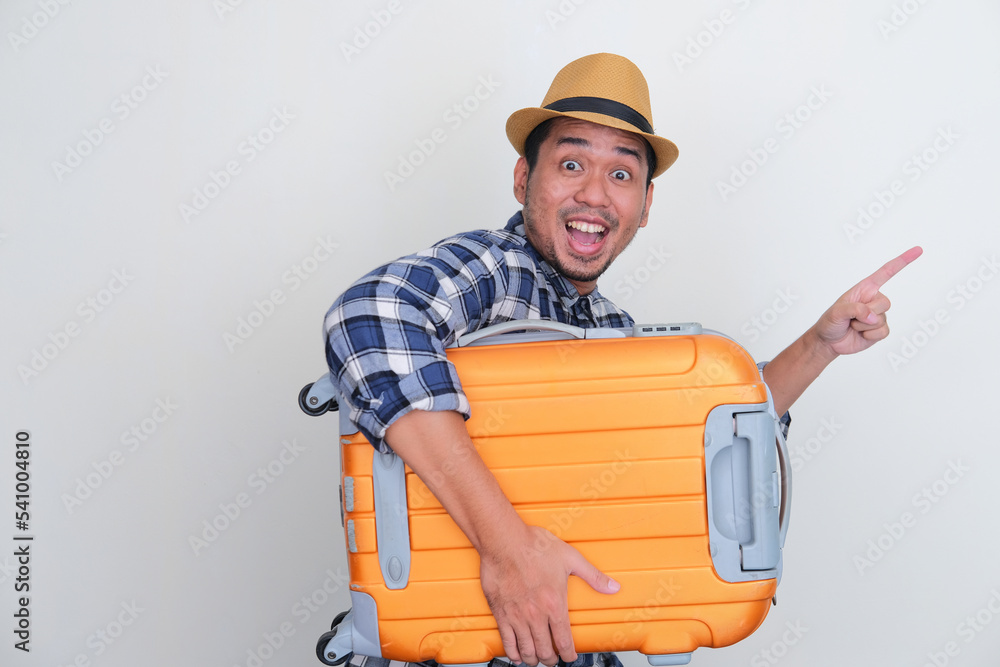 Adult Asian man pointing to the left with excited expression while ...