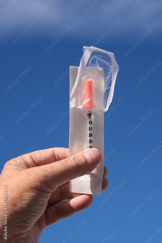 hand holding syringe package, unpacking it and un capping needle ...
