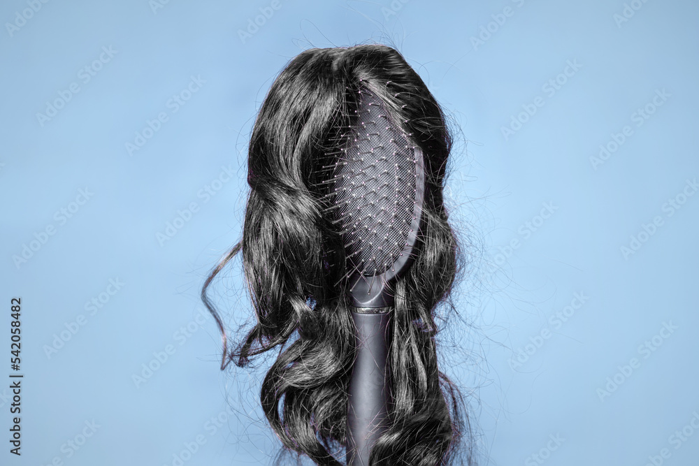 Wig, alopecia and chignon. Comb with black wig on a blue background ...