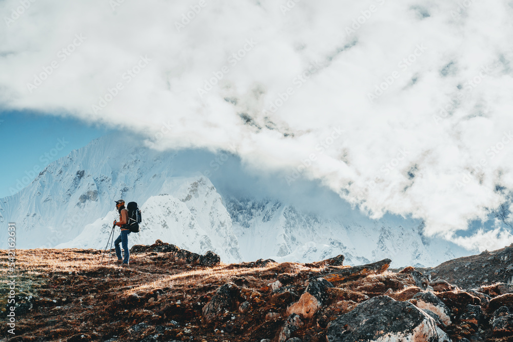 Young tourist walk along high altitude track among snowy and cloudy ...