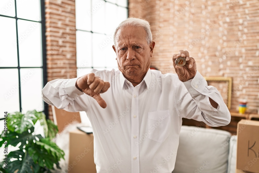 Senior man with grey hair holding virtual currency bitcoin with angry ...