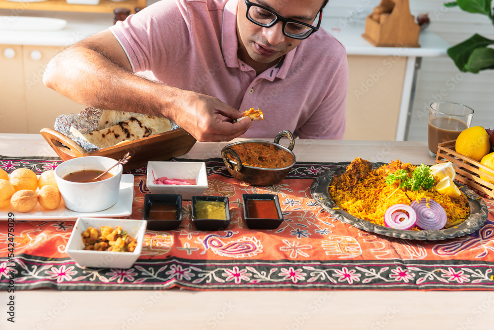 Indian men using hand to be picking up Indian food placed on the table ...