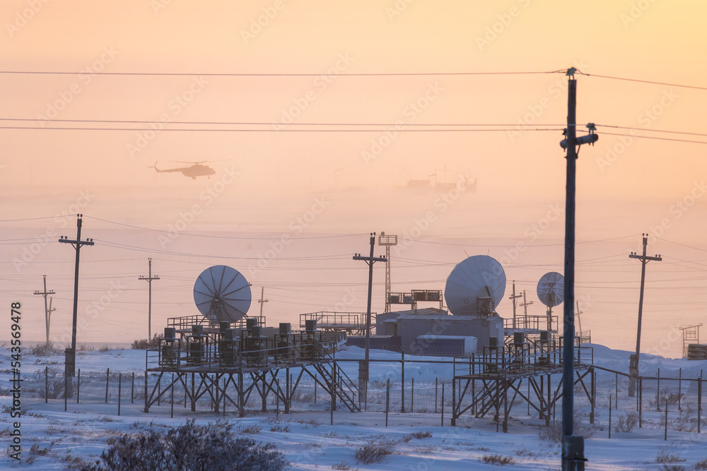 Industrial arctic landscape. A helicopter is landing at an airstrip in ...