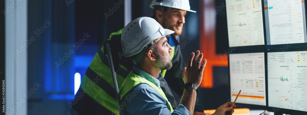 Group of engineers control process of production uses computer with modern SCADA system. Team of ...