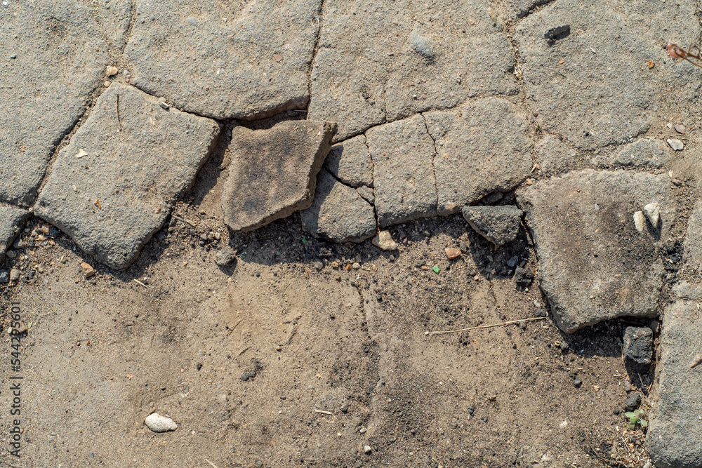 Background with old cracked asphalt covered with sand and gravel ...