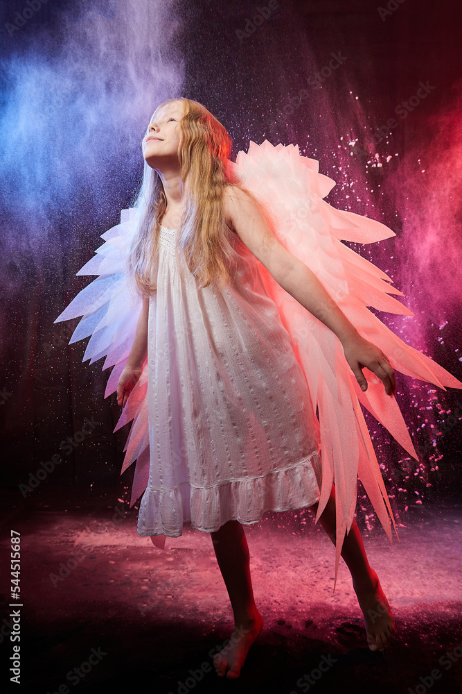 Photo Stock A girl in a white shirt, wings and with long hair, looking ...