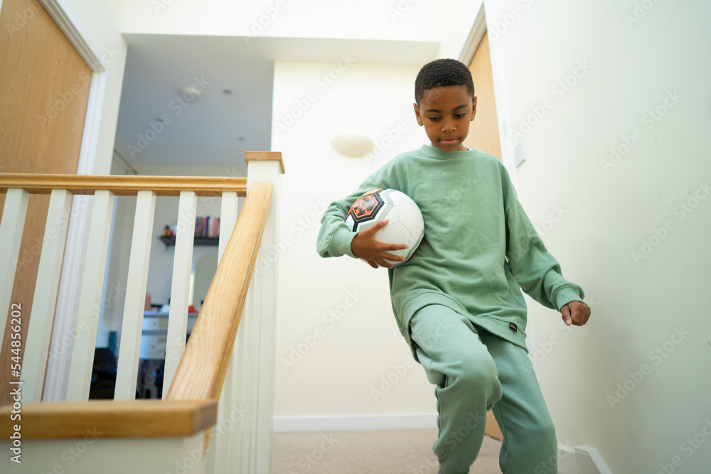 Boy walking down stairs with soccer ball Stock Photo | Adobe Stock