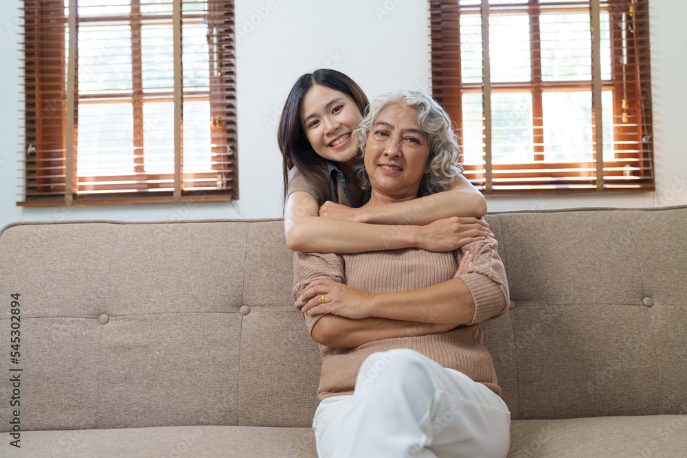 Asian family mother daughter give hug cuddle embrace at home sofa, Grown up daughter hugging ...