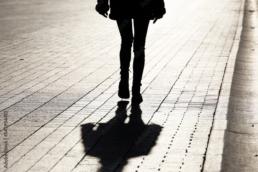 Black silhouette and shadow of slim girl walking on a street. Female ...