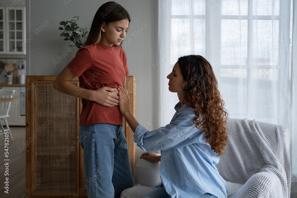 Worried concerned mother parent examining child stomach belly at home ...