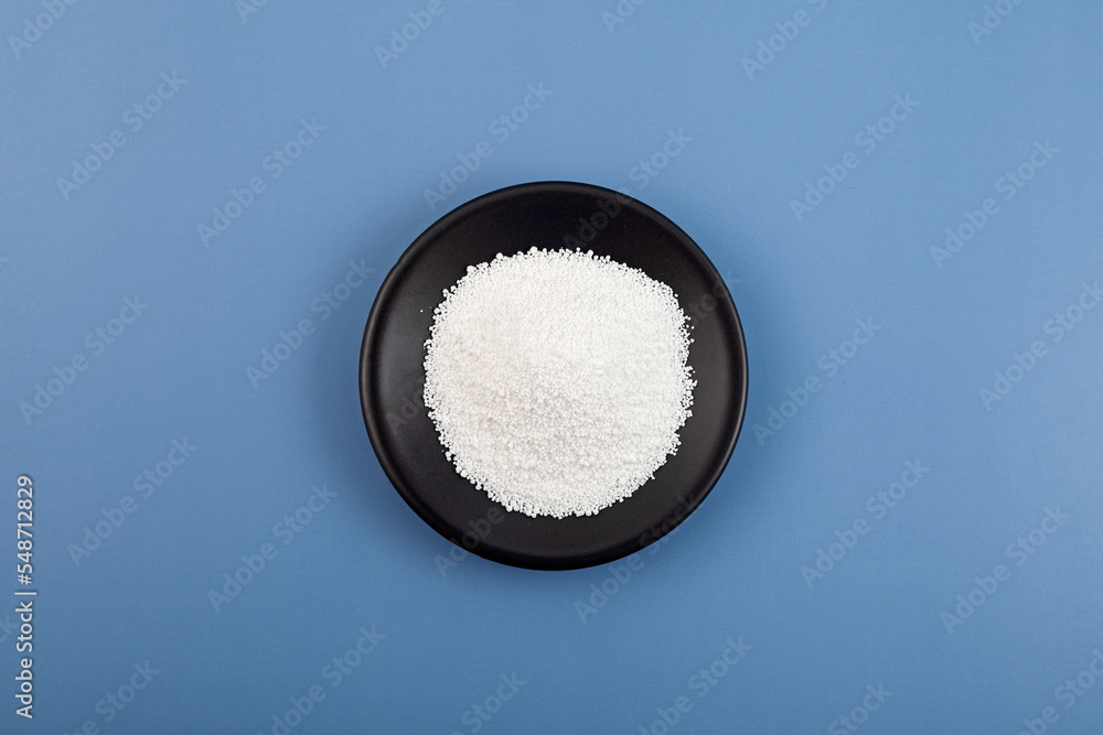 Sodium benzoate, sodium salt of benzoic acid in dark dish on blue ...