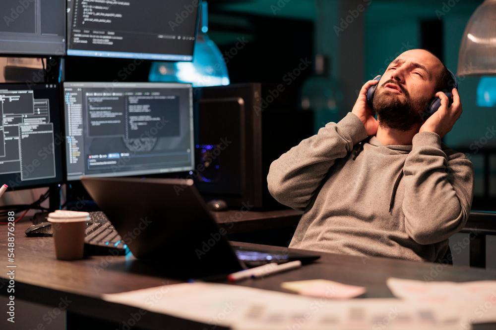 Software developer singing song in office, using multiple screens to ...
