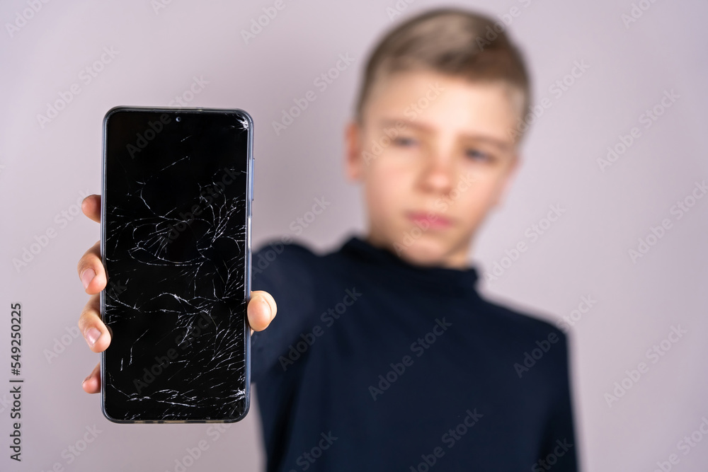Portrait frustrated kid with broken mobile phone screen, shocked with ...