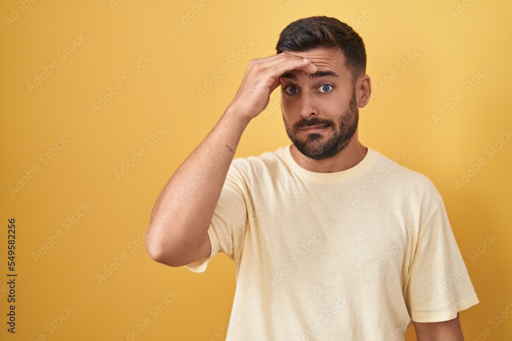 Handsome hispanic man standing over yellow background worried and ...