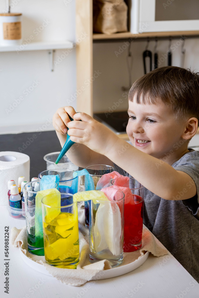 Cute baby boy learning mixing different colors with water and paint in ...