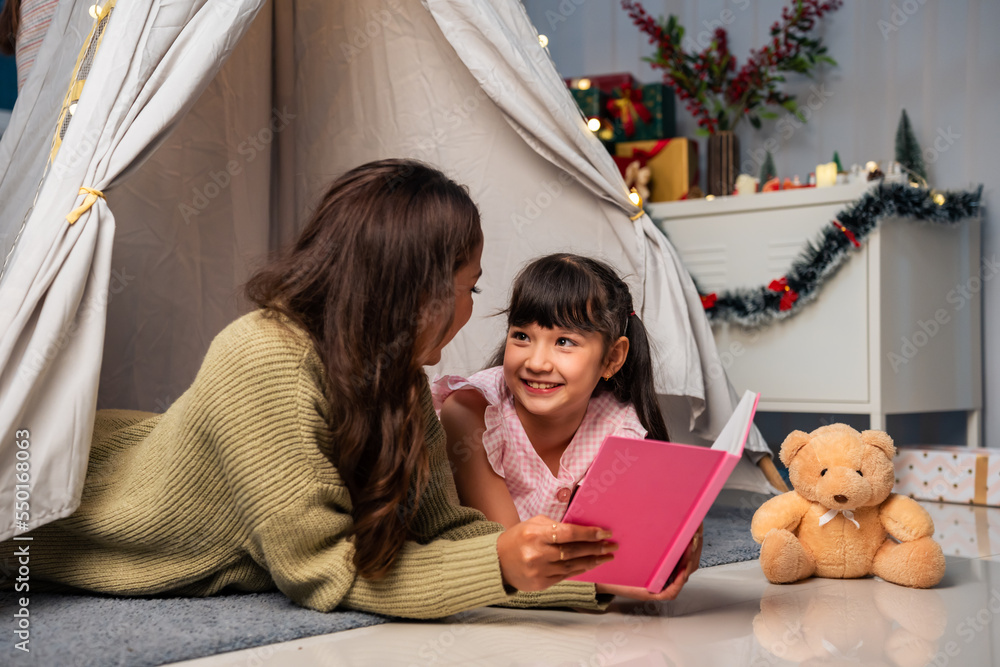 Caucasian mother read story and telling a fairy tale to young daughter ...