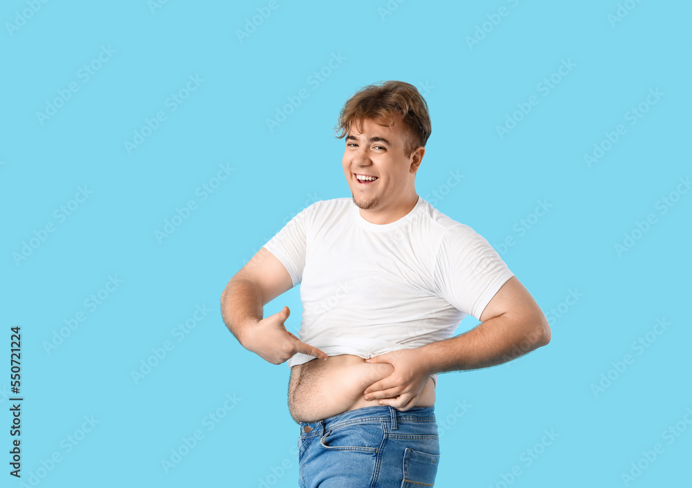 Young overweight man pointing at his belly on blue background Stock ...