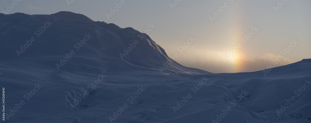 Fogbow appearing on the horizon over the snowy, mountainous landscape ...