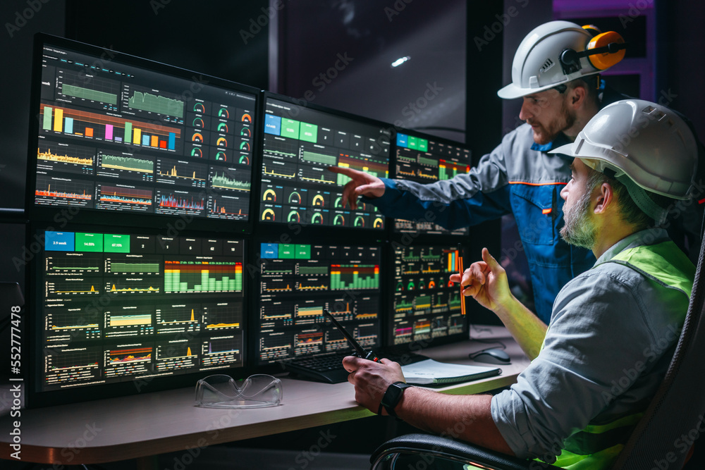 Head engineer and worker following factory production line uses screens ...