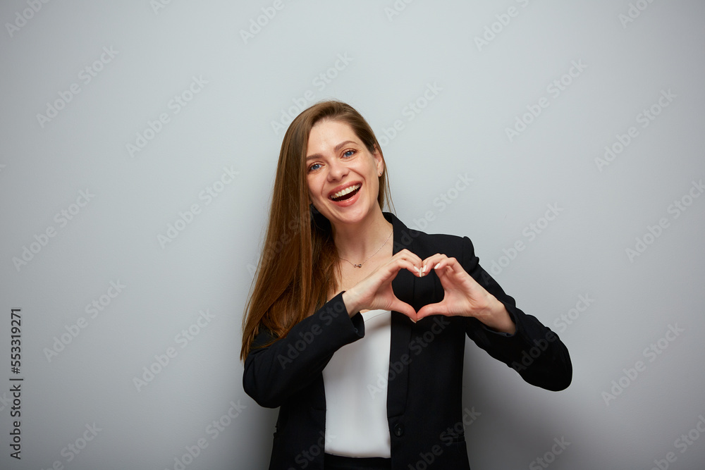 Smiling business woman in black suit holding heart figure with fingers ...