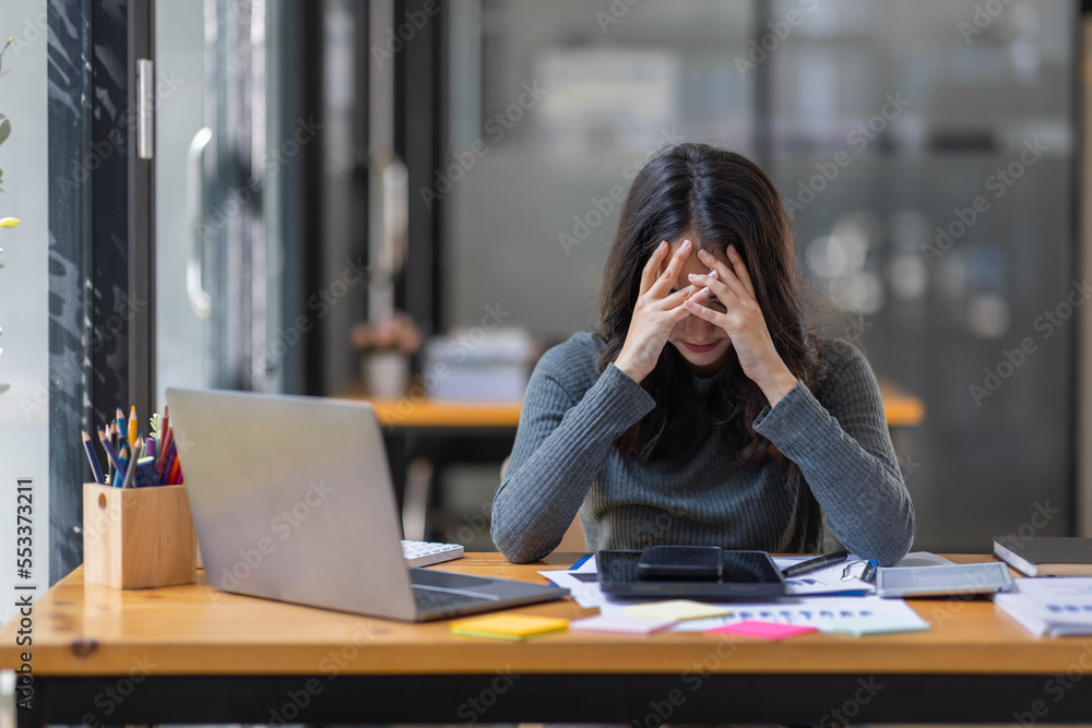 Portrait of tired young business Asian woman work with documents tax ...