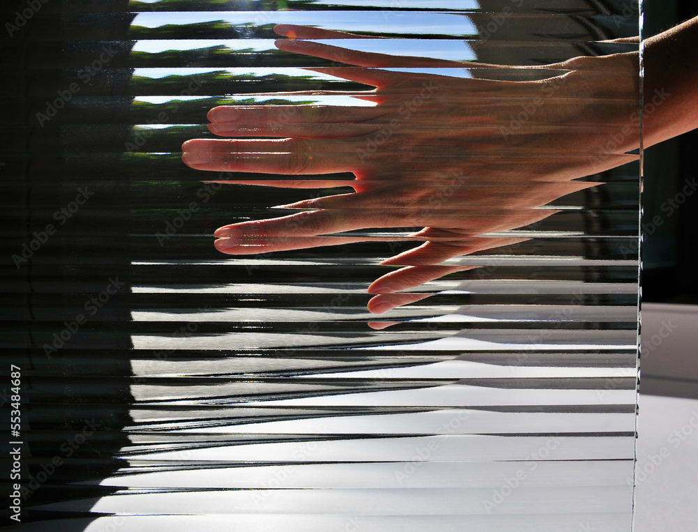Refraction of light creates distorted image of hand through corrugated ...