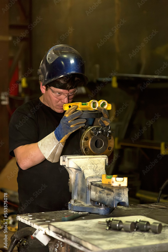 Journeyman pipe fitter aligns a flange using a level before tack ...