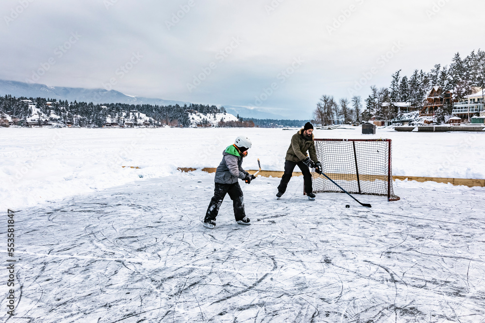 Father and his son playing hockey on a frozen Windermere Lake during ...