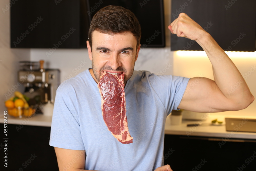 Muscular man eating beef and flexing biceps Stock Photo | Adobe Stock