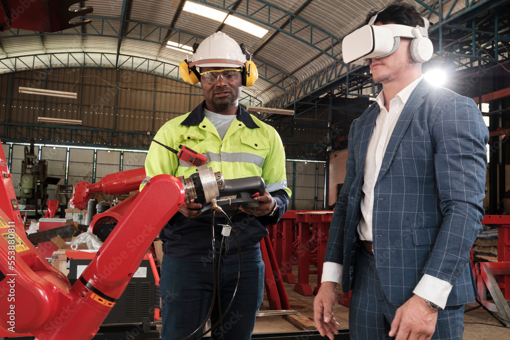 African American engineer demonstrates robotic arm control to customer ...