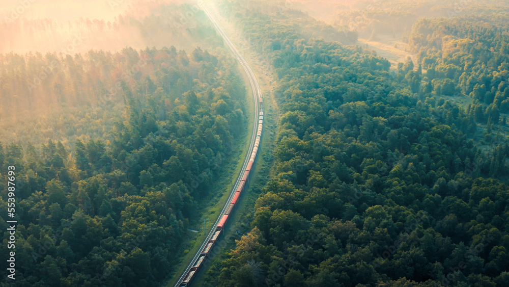 Cargo Train in summer morning forest at fog sunrise. Aerial view of ...