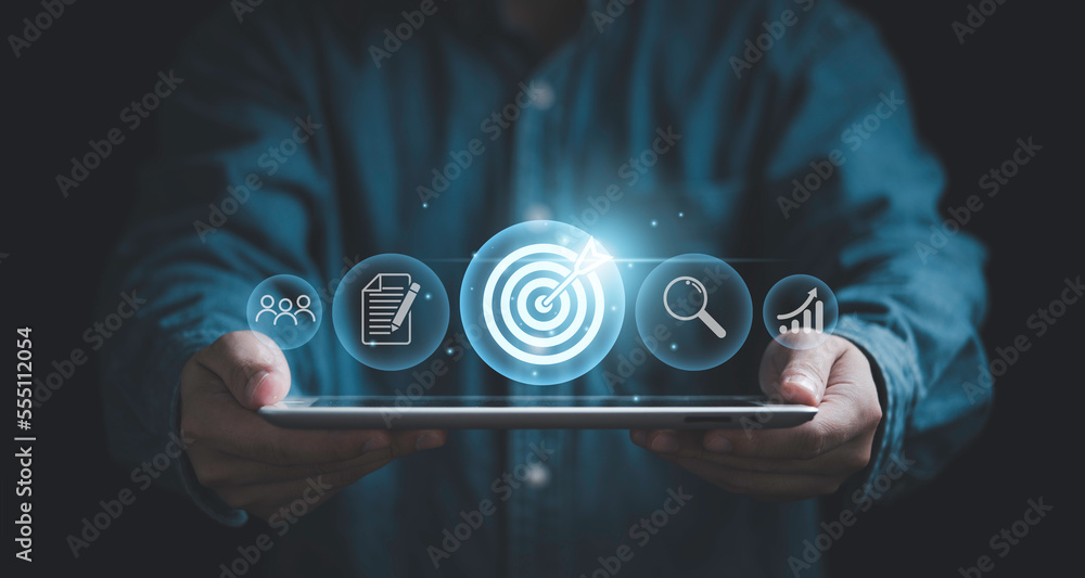 Businessman holding tablet with dartboard for setup business objective ...