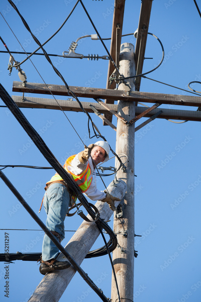 Cable lineman installing new suspension wire from power pole brace ...