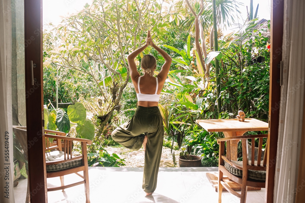 Young mindful woman does yoga on the terrace of house with a view of ...