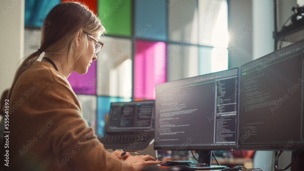 Female Software Engineer Writing Lines of Code on Professional Multiple Display PC Setup In ...