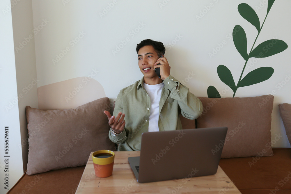 Hispanic young man sitting in coffee shop with his laptop and working ...