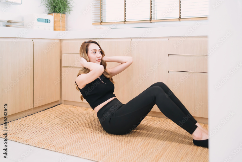 exercising woman doing sit up kitchen. healthy woman on mat control ...