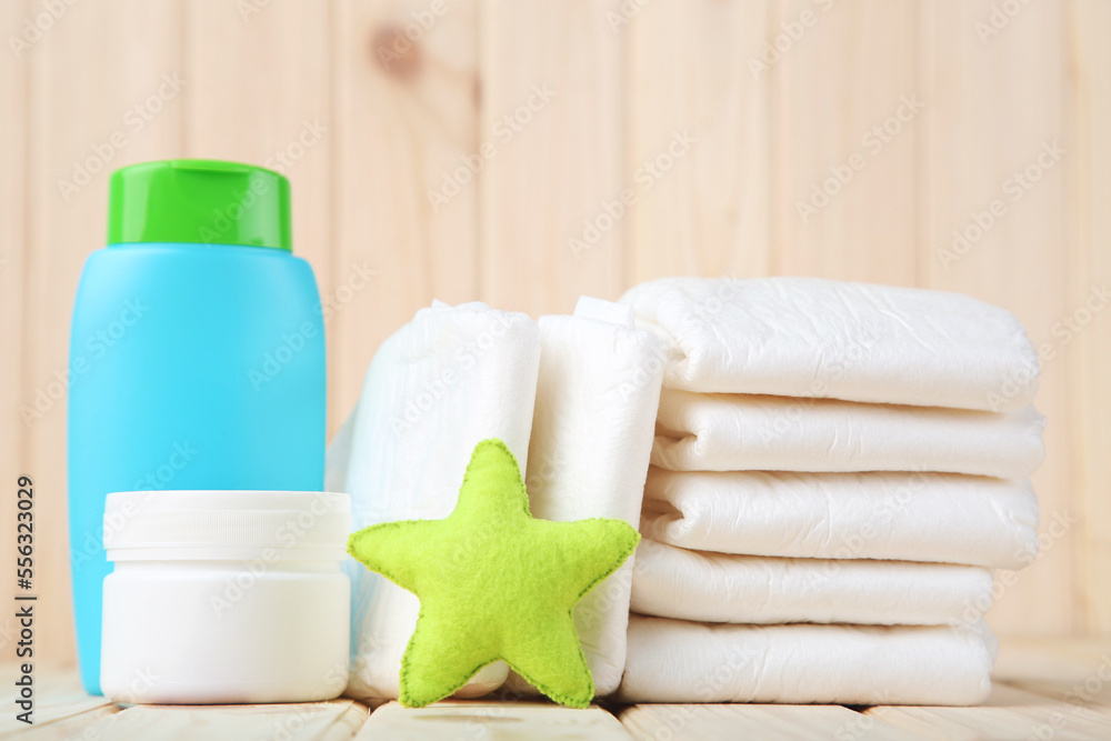 Baby diapers with toiletries and star toy on brown wooden background ...