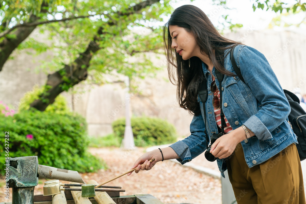 side view of Asian female traveler filling the dipper to wash her hands ...