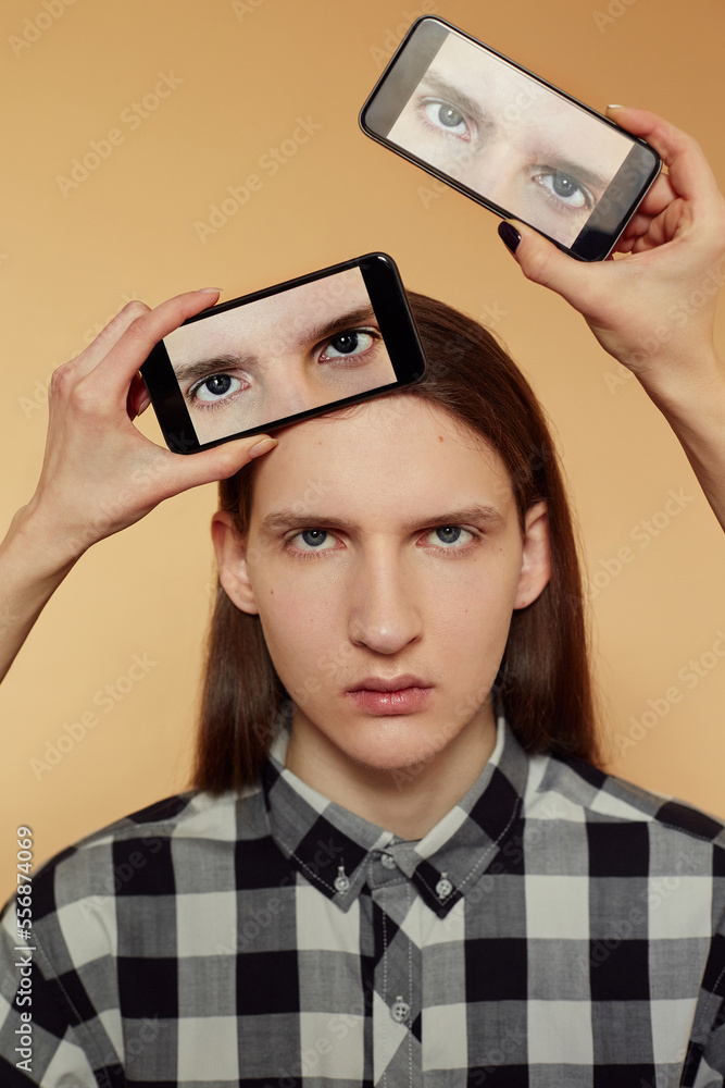 Crop hands holding modern smartphone with eyes photos near handsome ...