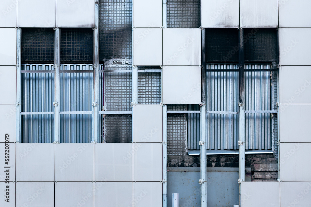 Broken, badly fixed wall of an industrial building. Fallen off cladding ...
