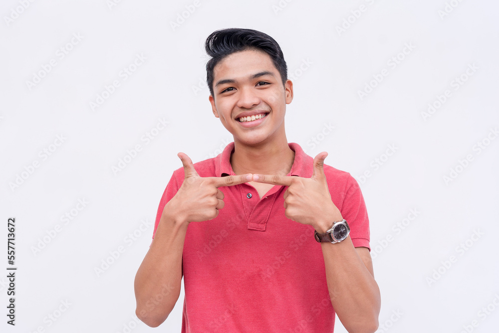 A young man makes the two fingers pointing gesture, trying to look shy ...