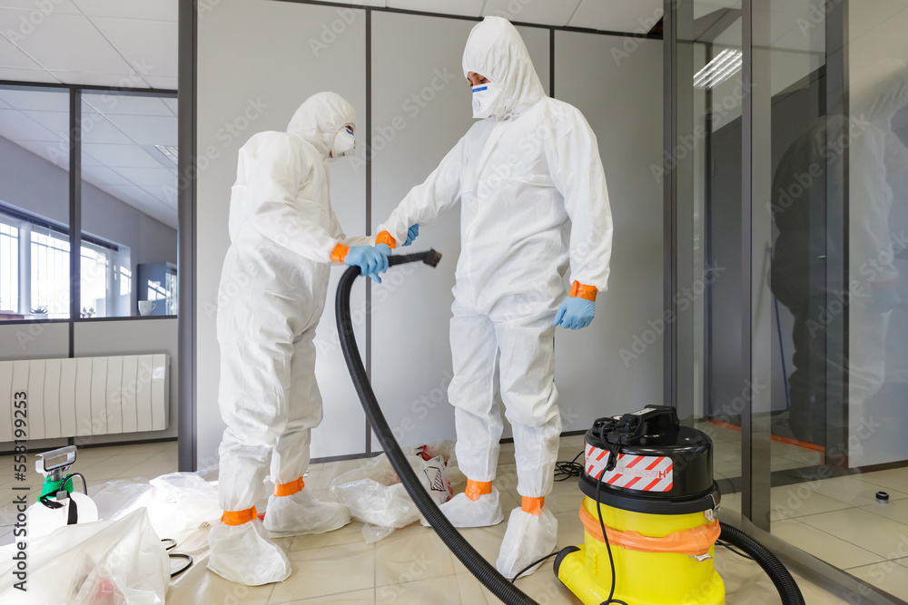 Operators in type 5/6 hazmat suits mutually performing decontamination ...