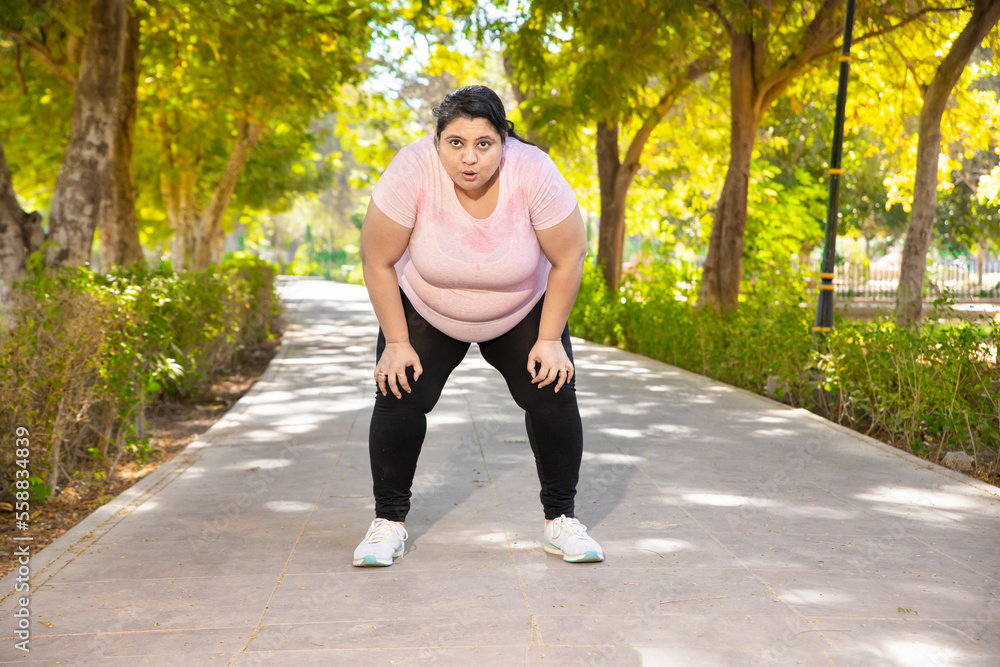 Overweight tired exhausted indian woman stooped after jogging workout ...