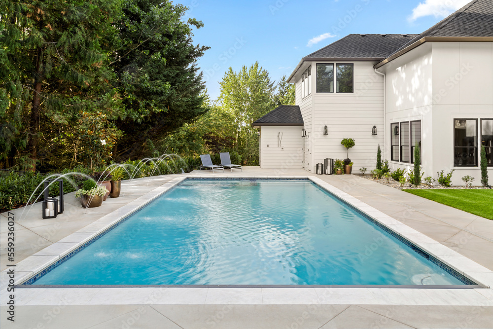 Beautiful home exterior and large swimming pool on sunny day with blue ...