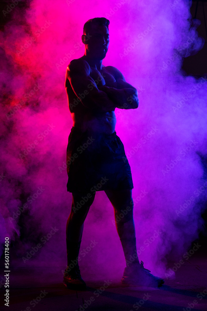 Muscular man standing in neon light Stock Photo | Adobe Stock