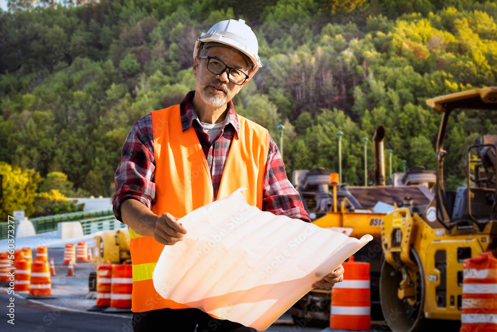 Foreman, wearing a safety vest and safety hat, supervises workers and ...