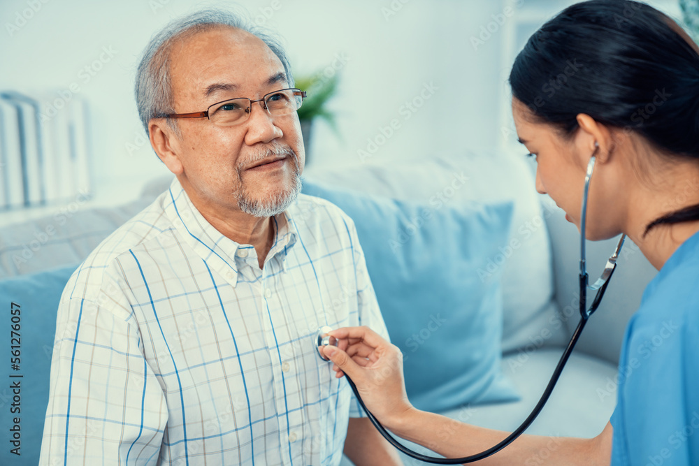 Caring young female doctor examining her contented senior patient with ...