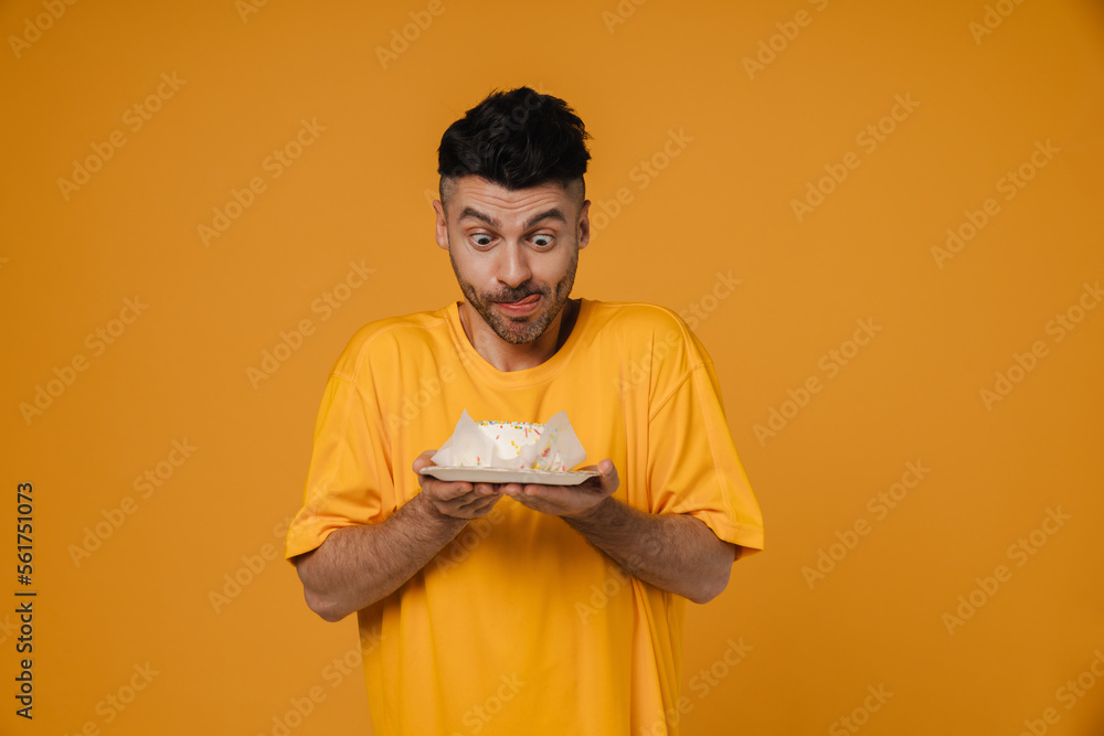 Excited hungry man holding cake and licking his lips isolated over ...